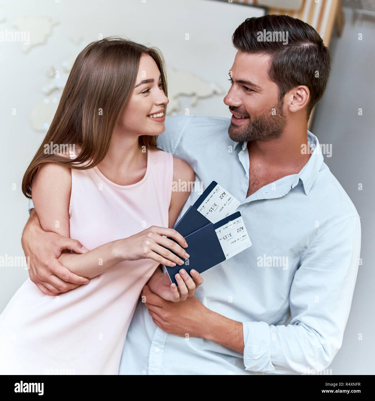 Joyful couple looking to each other and holding passport with flying ...
