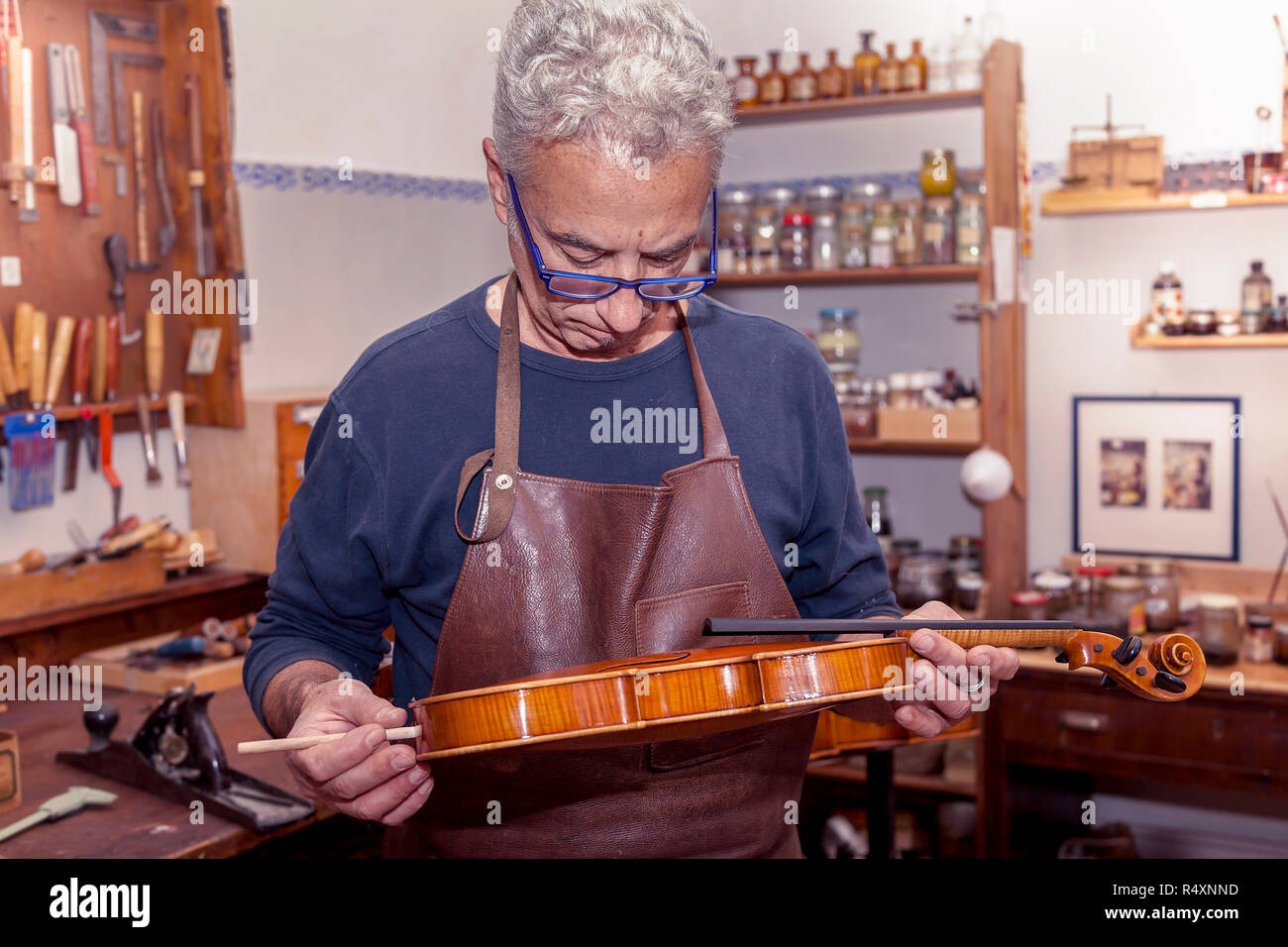 portrait of mature violin maker while testing the violins in his ...