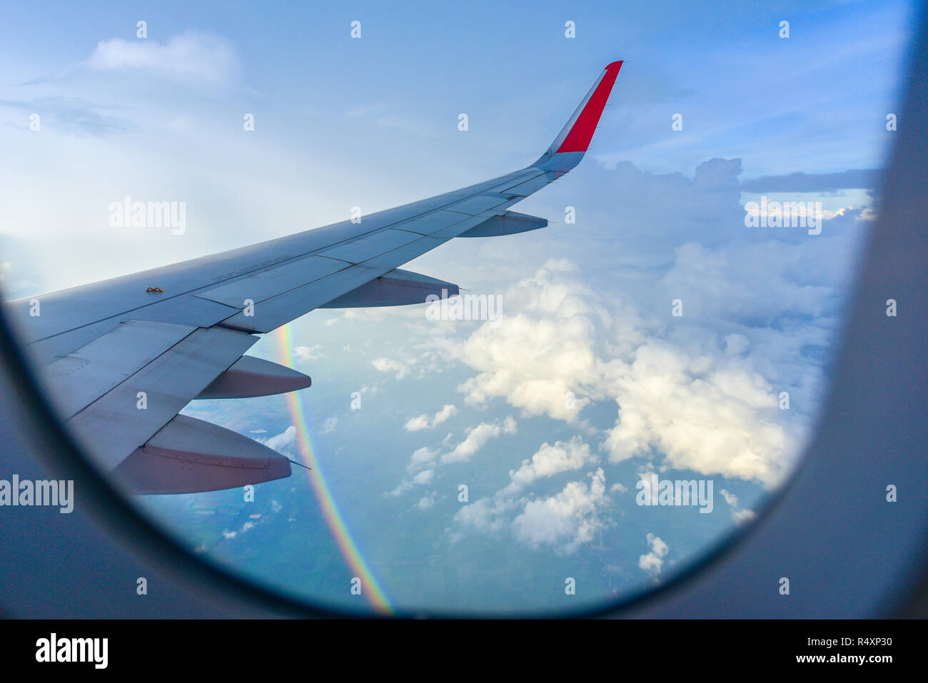 Wing of an airplane flying above the clouds and rainbow look from cabin ...