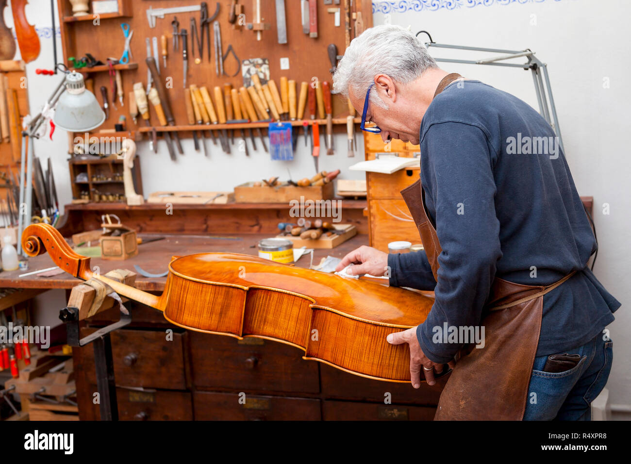portrait of mature violin maker while testing the violins in his ...