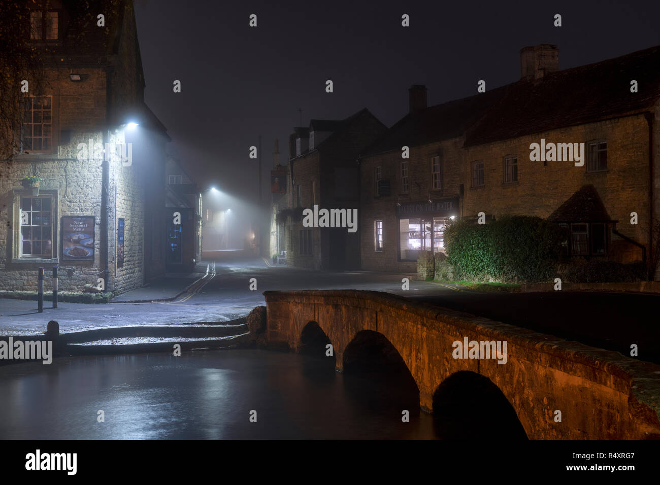 Mist and fog before dawn in the cotswold village of Bourton on the ...