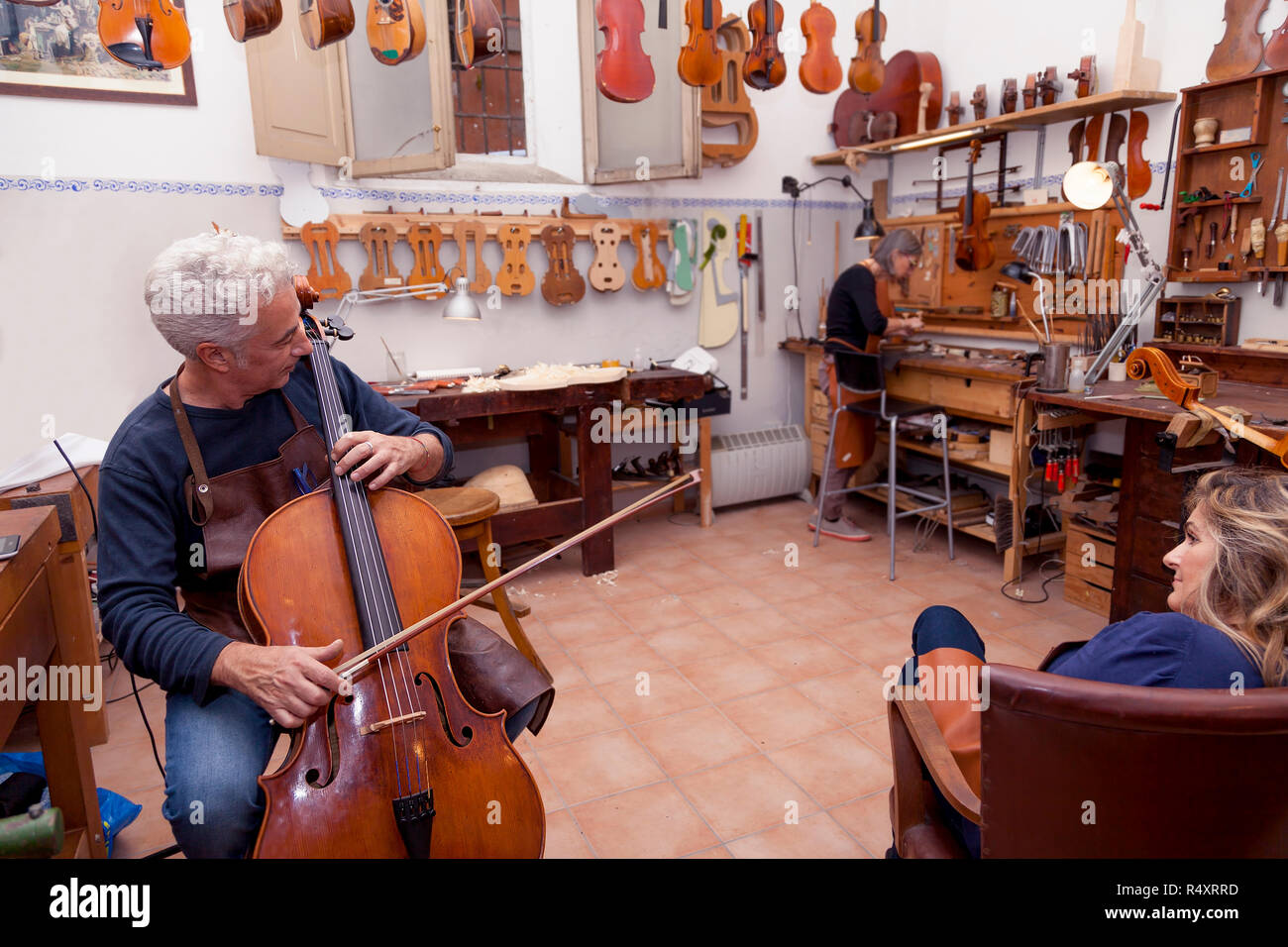 portrait of mature violin maker while testing the violins in his ...