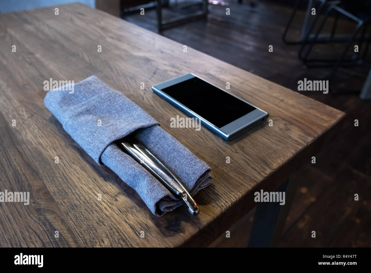 Mobile phone with cutlery set on wooden table in restaurant. Smartphone ...