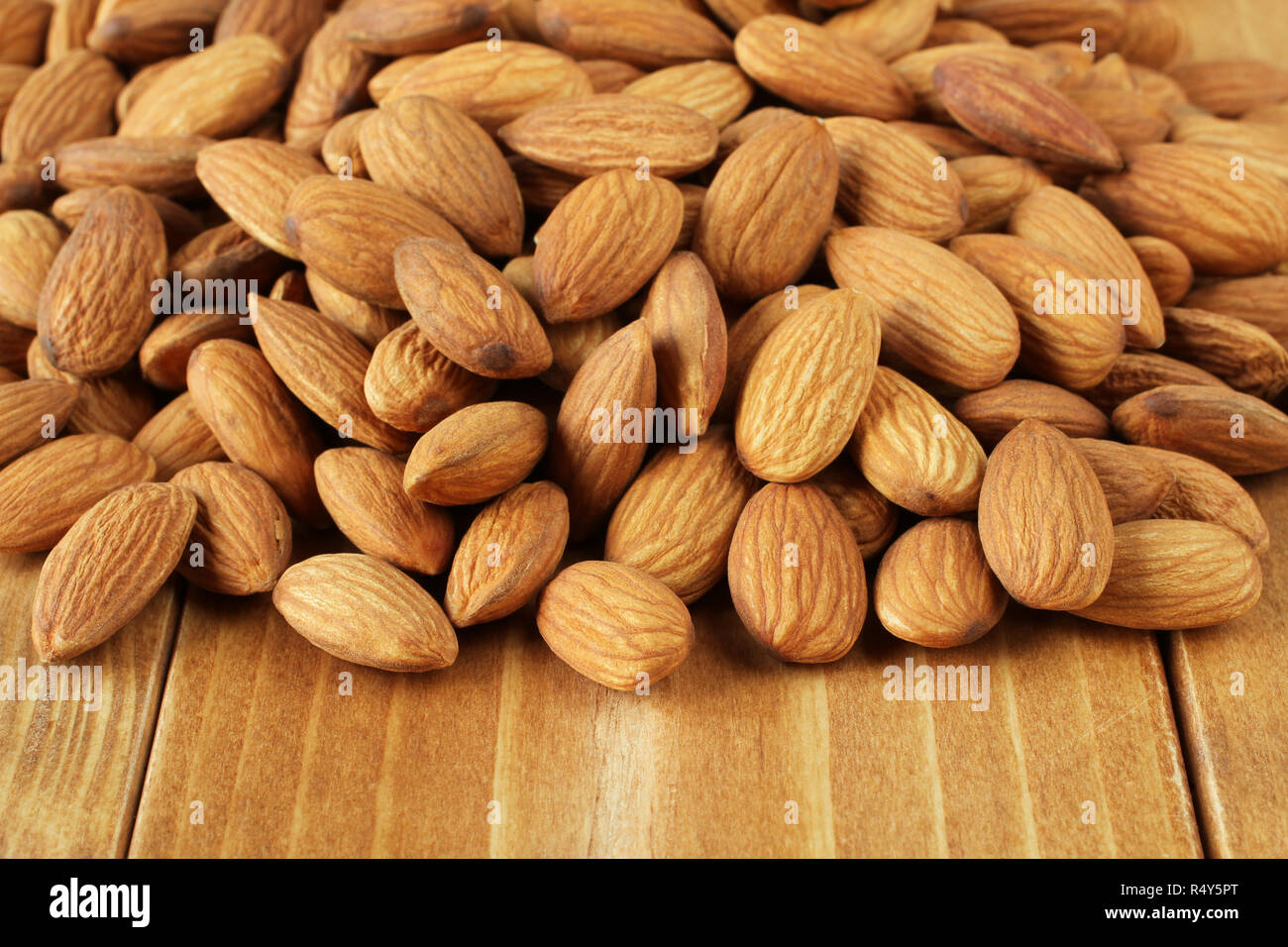 A bunch of almonds on brown toned wooden table. Closeup Stock Photo - Alamy