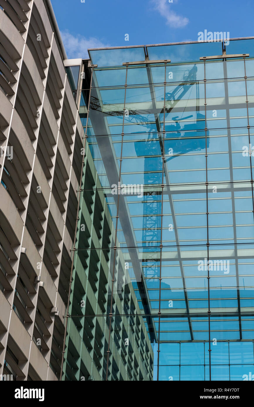 a tower crane reflected in the glass of tall office buildings in ...