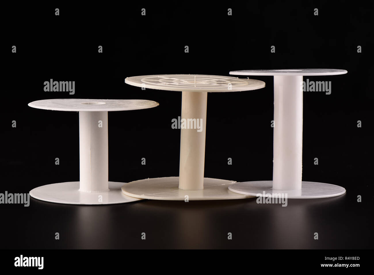 Three plastic empty spools of tape or strips of cloth on a black Stock ...