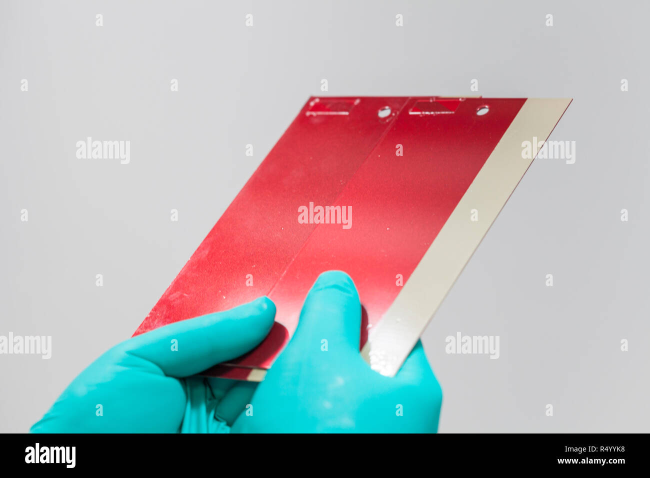 Laboratory technician checking and matching red paint in a color booth ...
