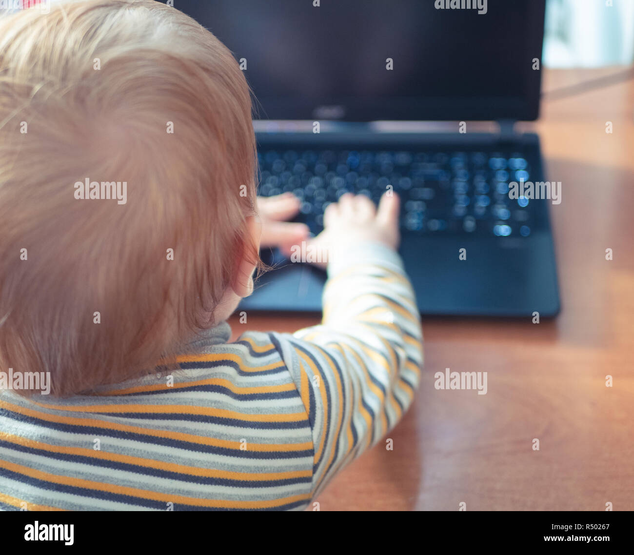 little caucasian white child boy typing on laptop keyboard. kids is our ...