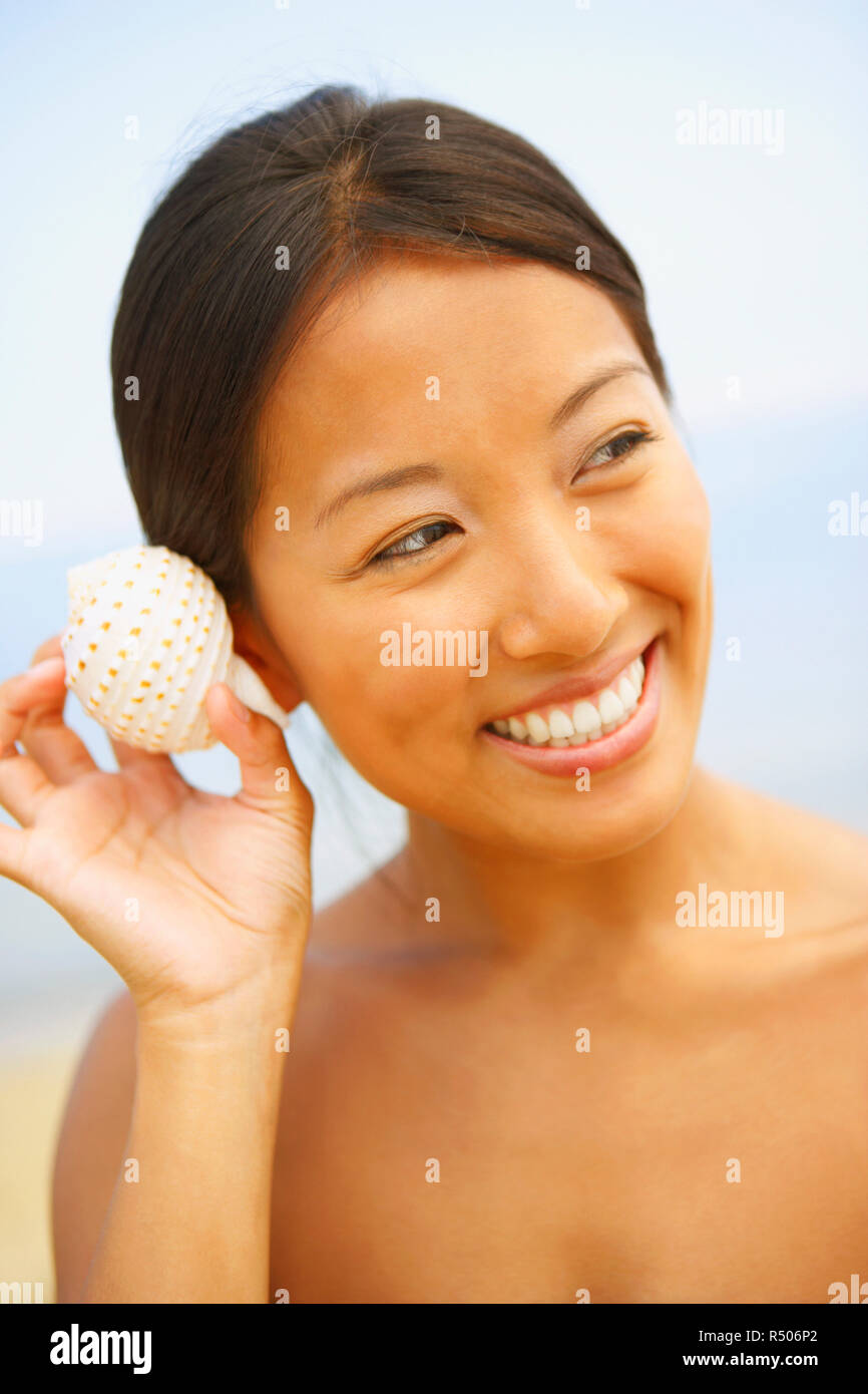 Woman holding seashell to ear hi-res stock photography and images - Alamy