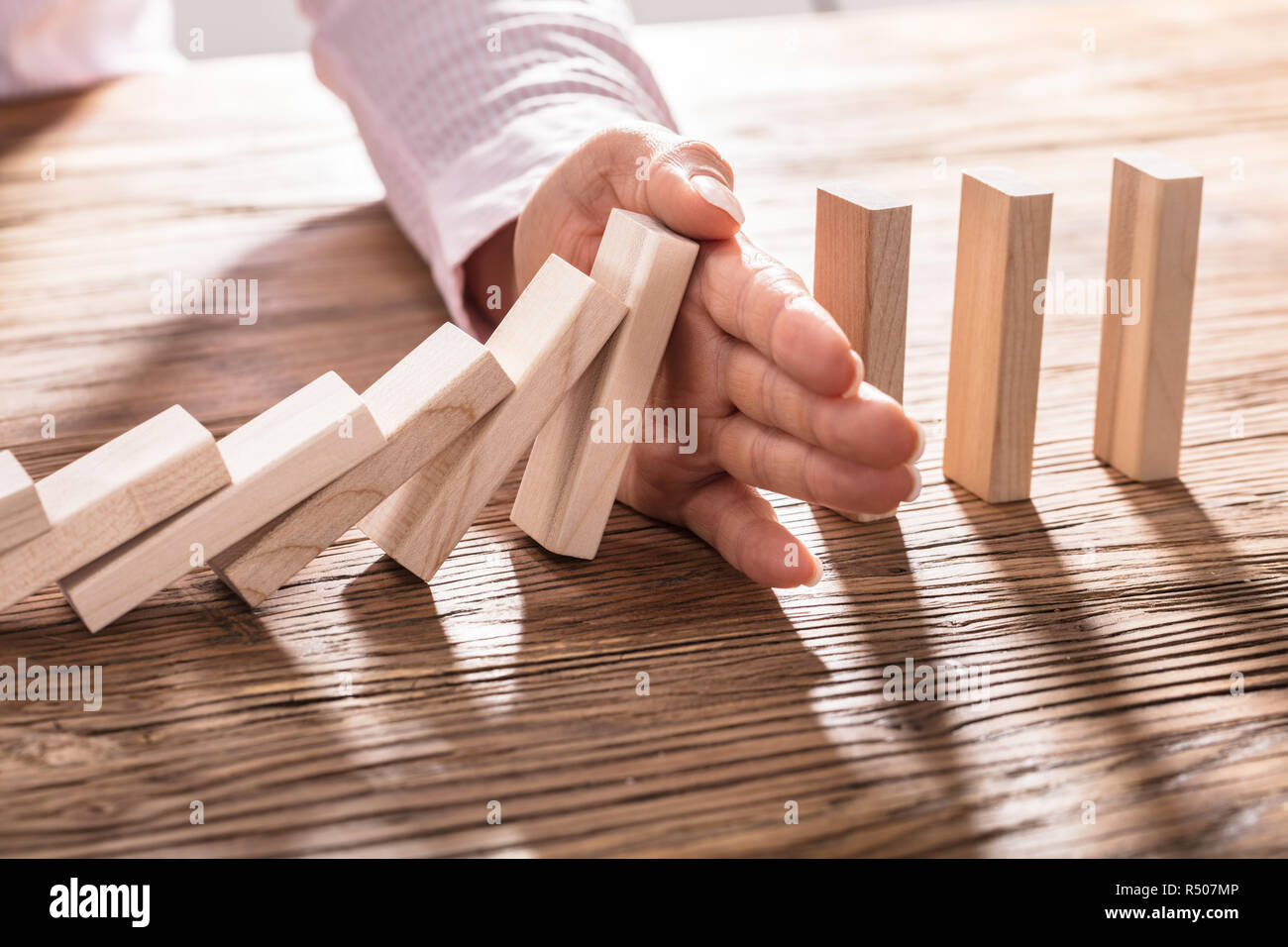 Business Woman's Hand Stopping Falling Blocks On Table Stock Photo - Alamy