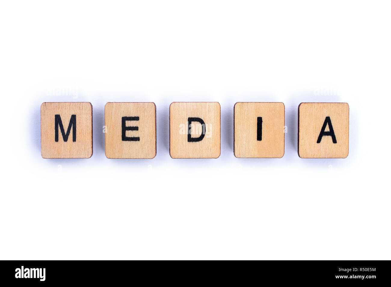 The word MEDIA, spelt with wooden letter tiles over a plain white ...