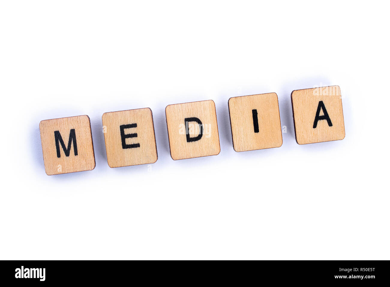 The word MEDIA, spelt with wooden letter tiles over a plain white ...