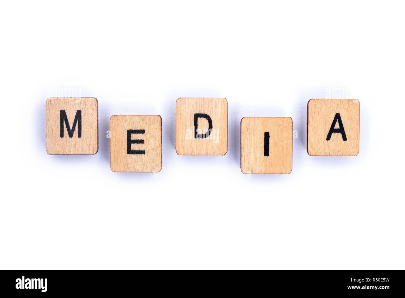The word MEDIA, spelt with wooden letter tiles over a plain white ...