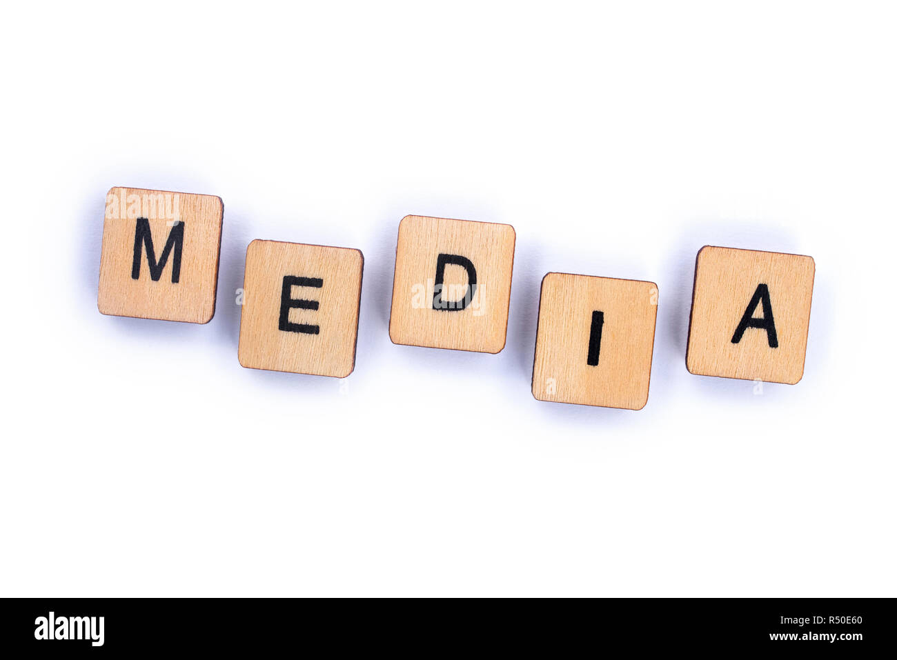 The word MEDIA, spelt with wooden letter tiles over a plain white ...