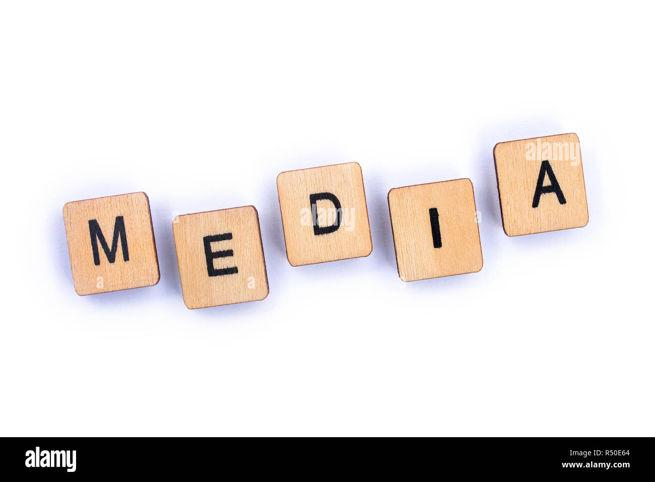 The word MEDIA, spelt with wooden letter tiles over a plain white ...