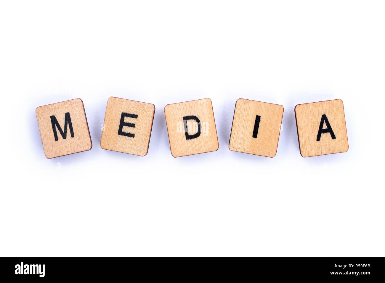 The word MEDIA, spelt with wooden letter tiles over a plain white ...