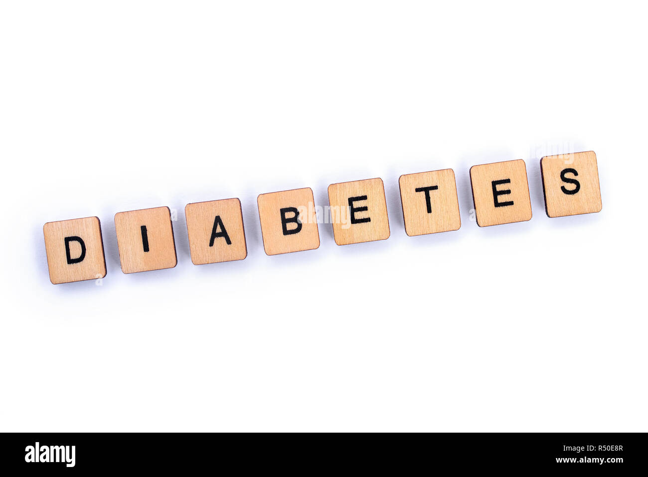 The word DIABETES, spelt with wooden letter tiles over a plain white ...
