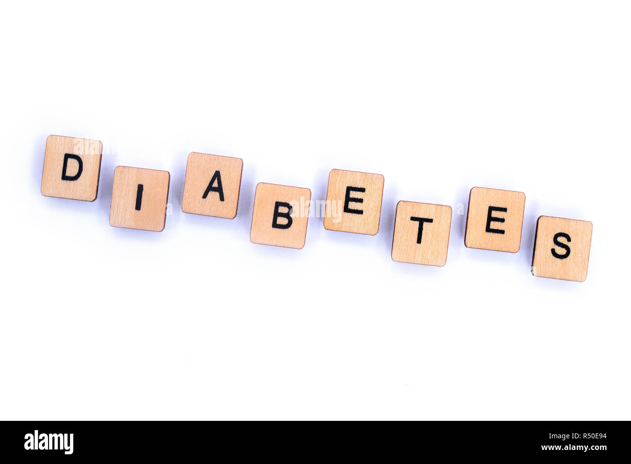 The word DIABETES, spelt with wooden letter tiles over a plain white ...