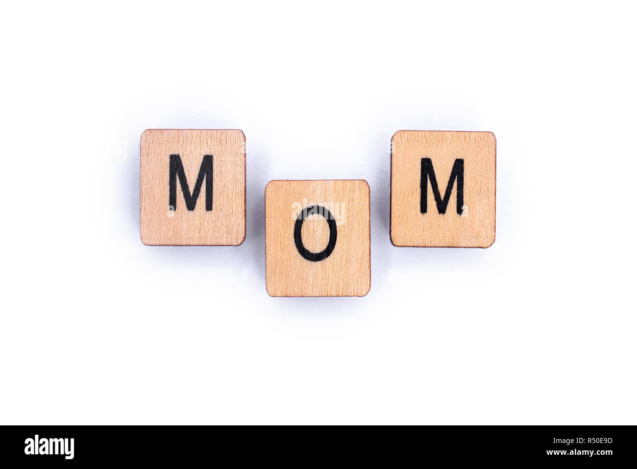 The word MOM, spelt with wooden letter tiles over a plain white ...