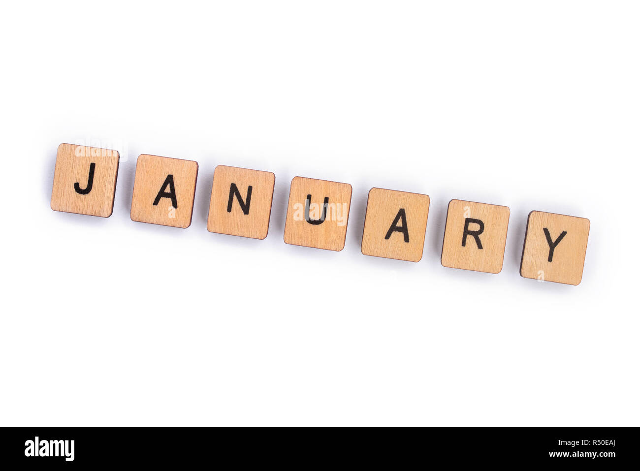 JANUARY, spelt with wooden letter tiles over a plain white background ...