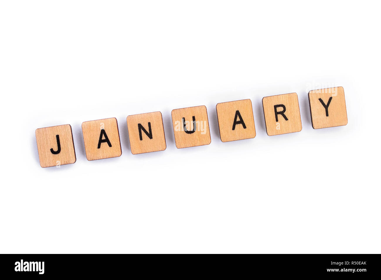 JANUARY, spelt with wooden letter tiles over a plain white background ...