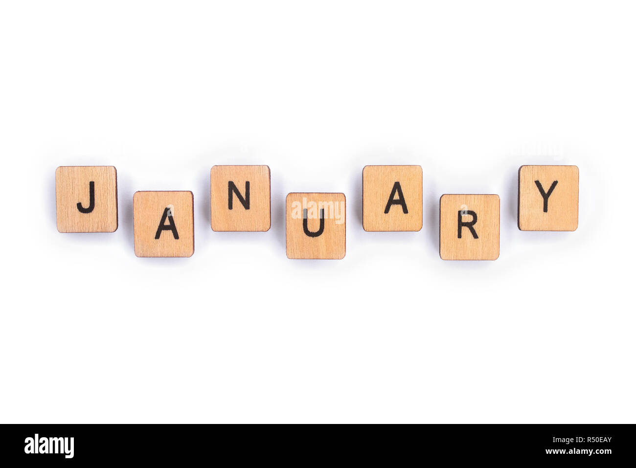 JANUARY, spelt with wooden letter tiles over a plain white background ...