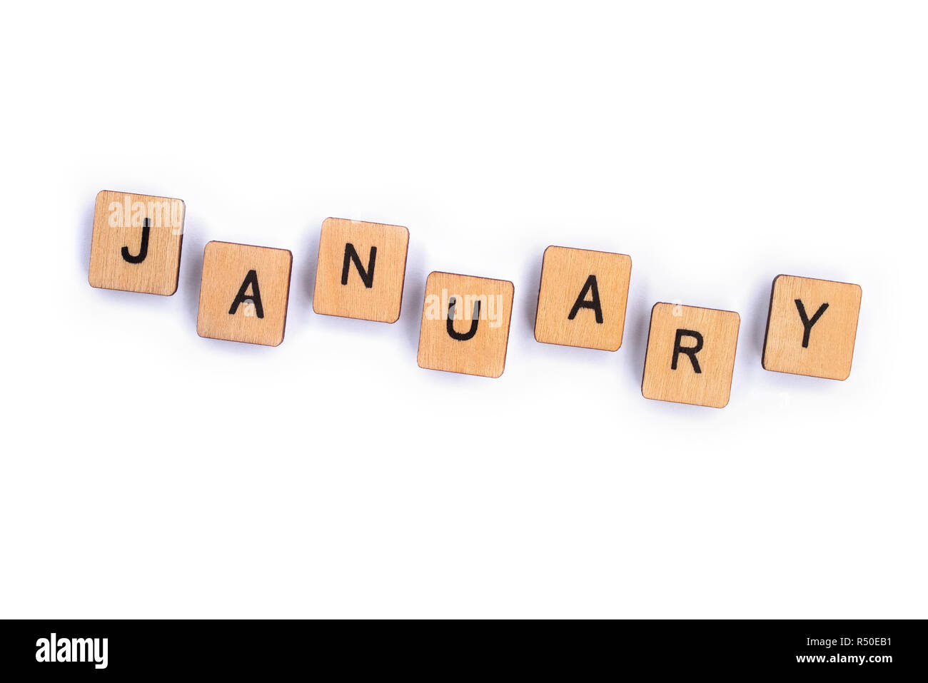 JANUARY, spelt with wooden letter tiles over a plain white background ...