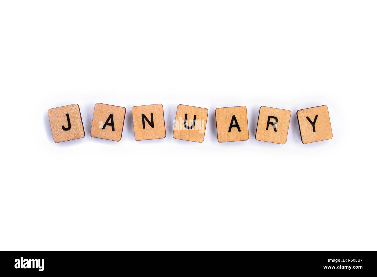 JANUARY, spelt with wooden letter tiles over a plain white background ...