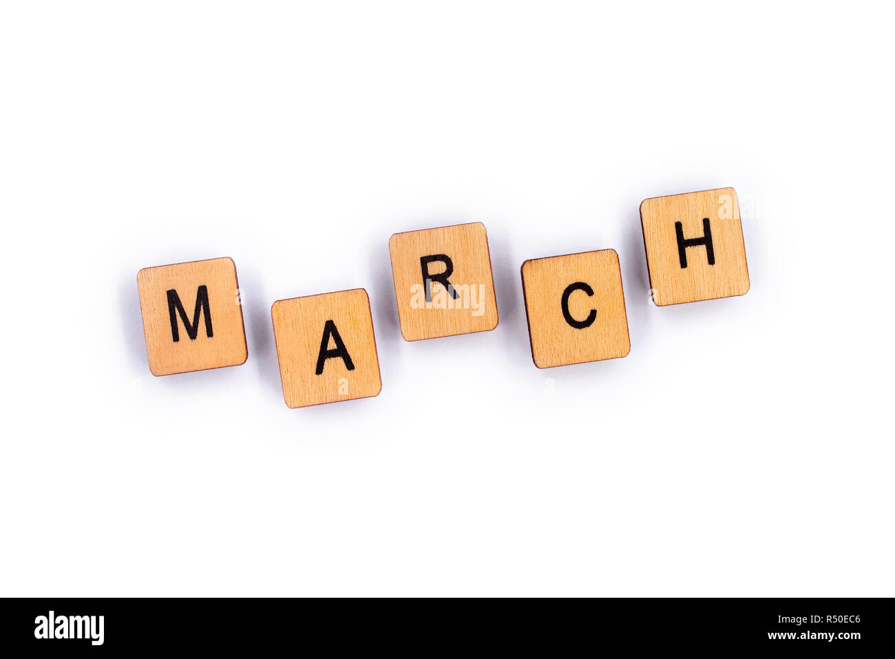 MARCH, spelt with wooden letter tiles over a plain white background ...