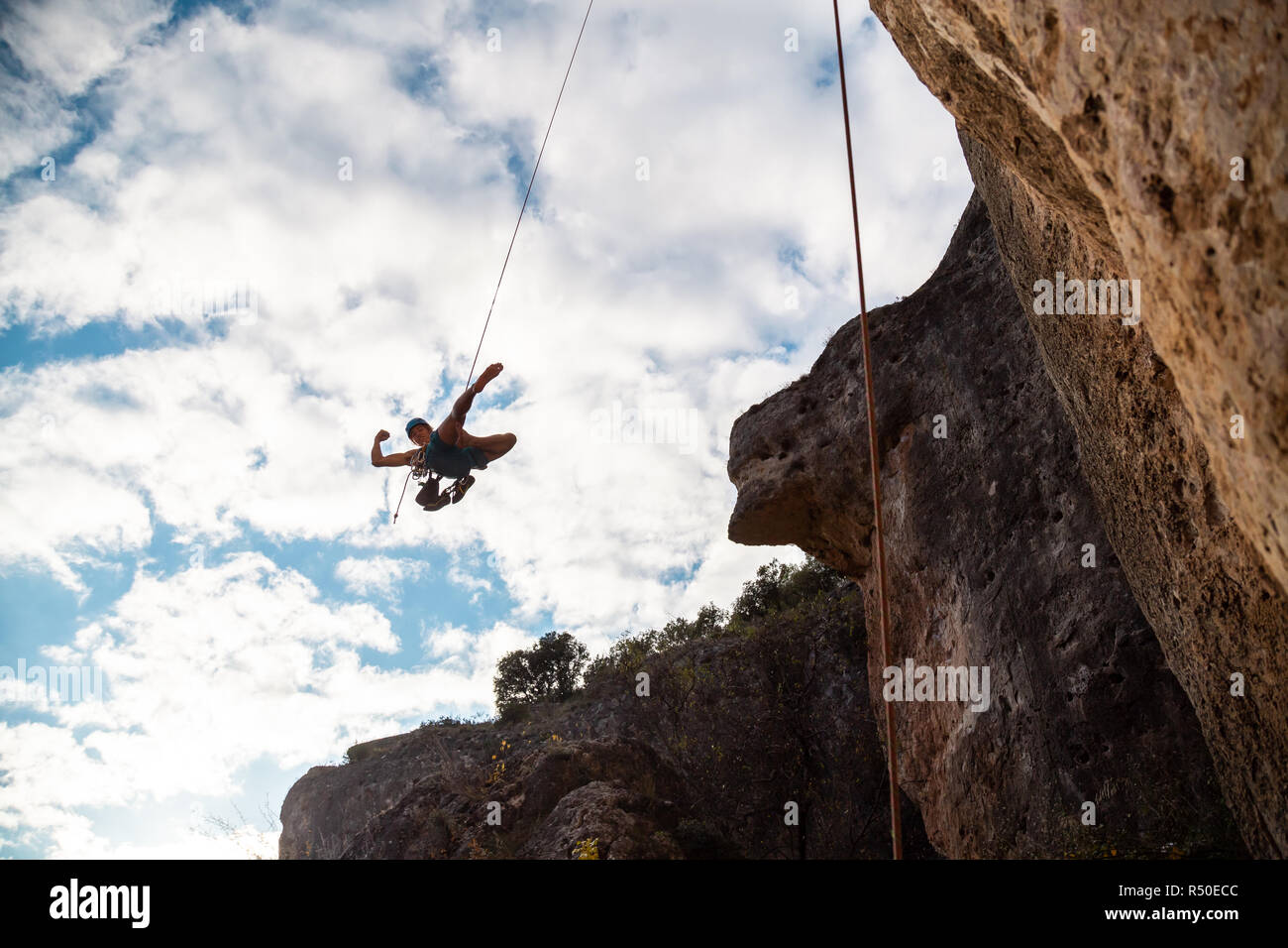 Man in hardhat hanging on rope while doing rappel and showing ...