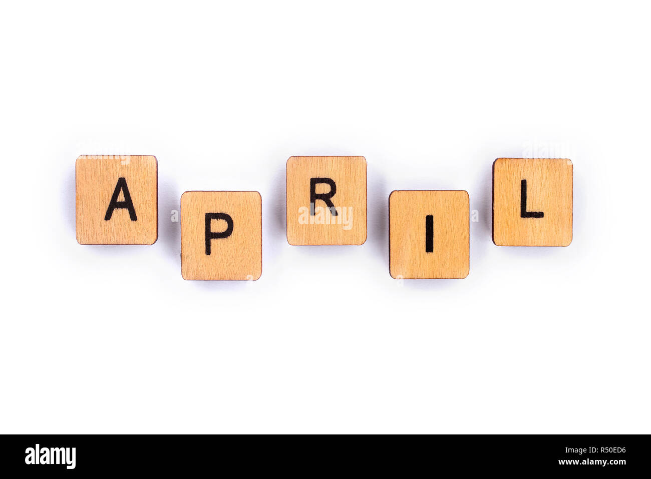APRIL, spelt with wooden letter tiles over a plain white background ...