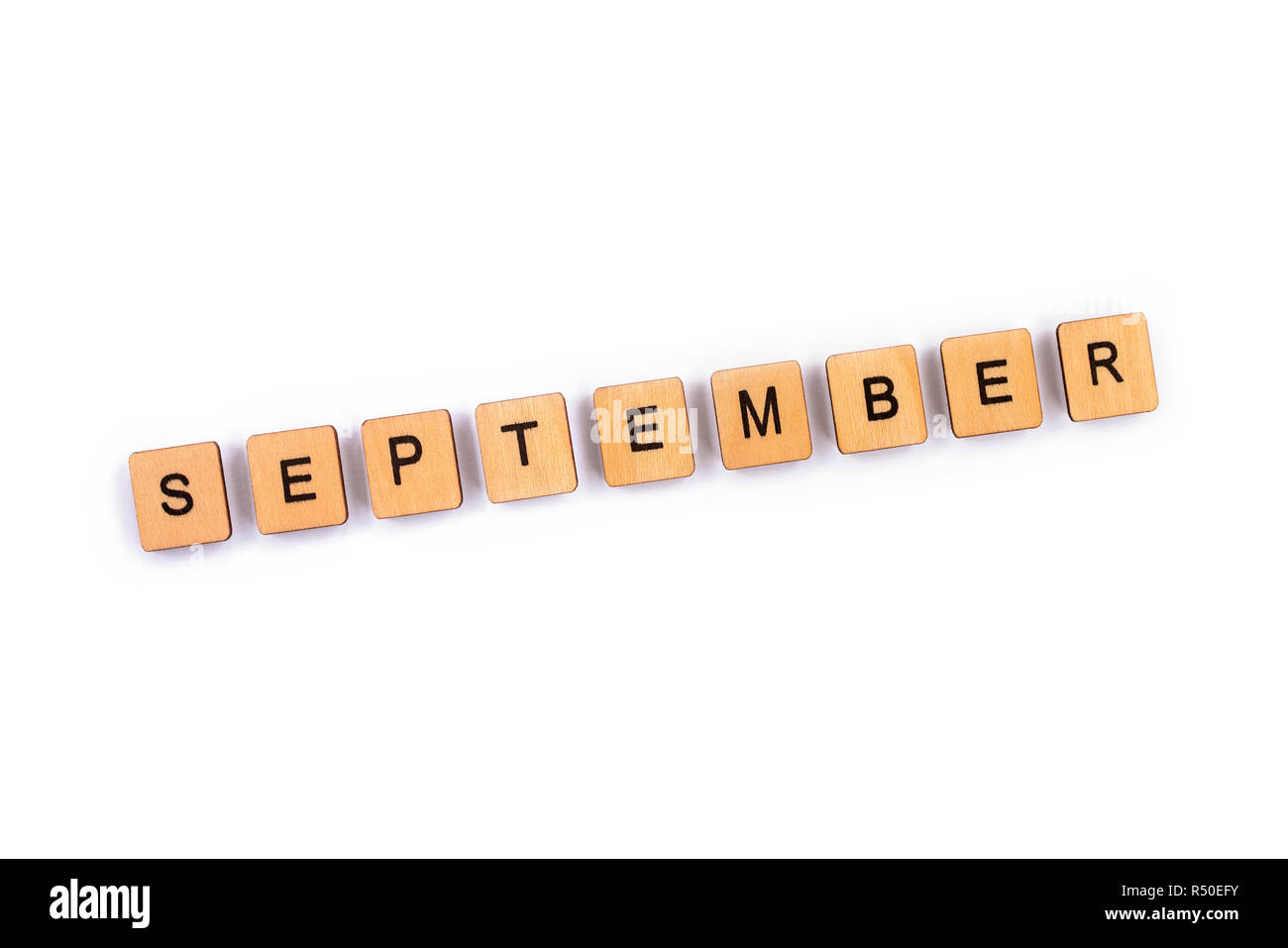 SEPTEMBER, spelt with wooden letter tiles over a plain white background ...
