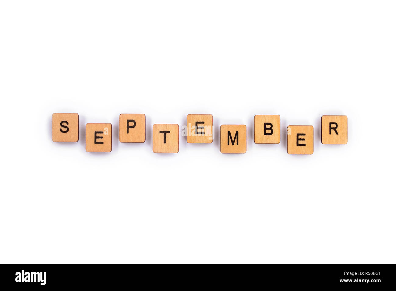 SEPTEMBER, spelt with wooden letter tiles over a plain white background ...