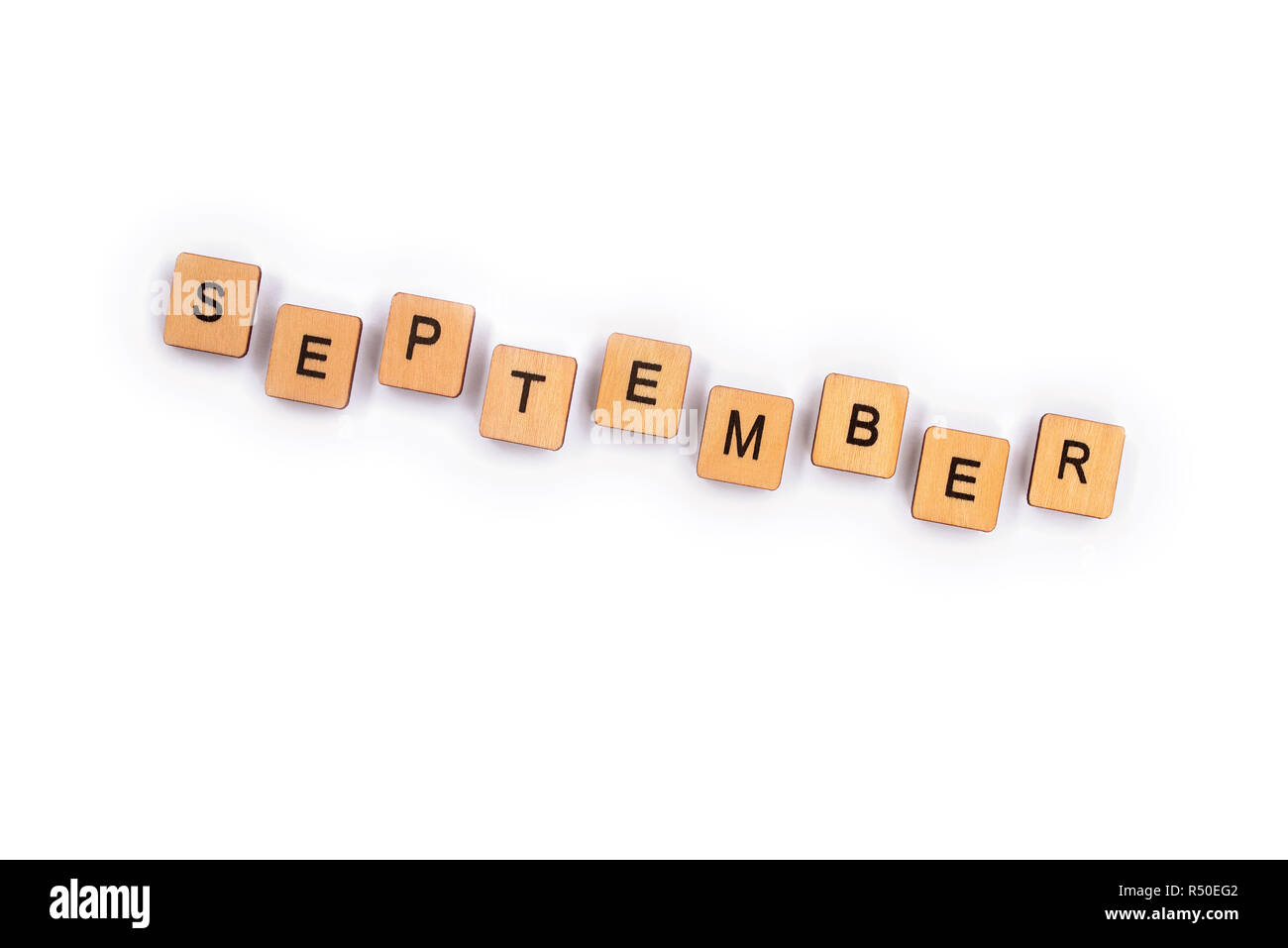SEPTEMBER, spelt with wooden letter tiles over a plain white background ...