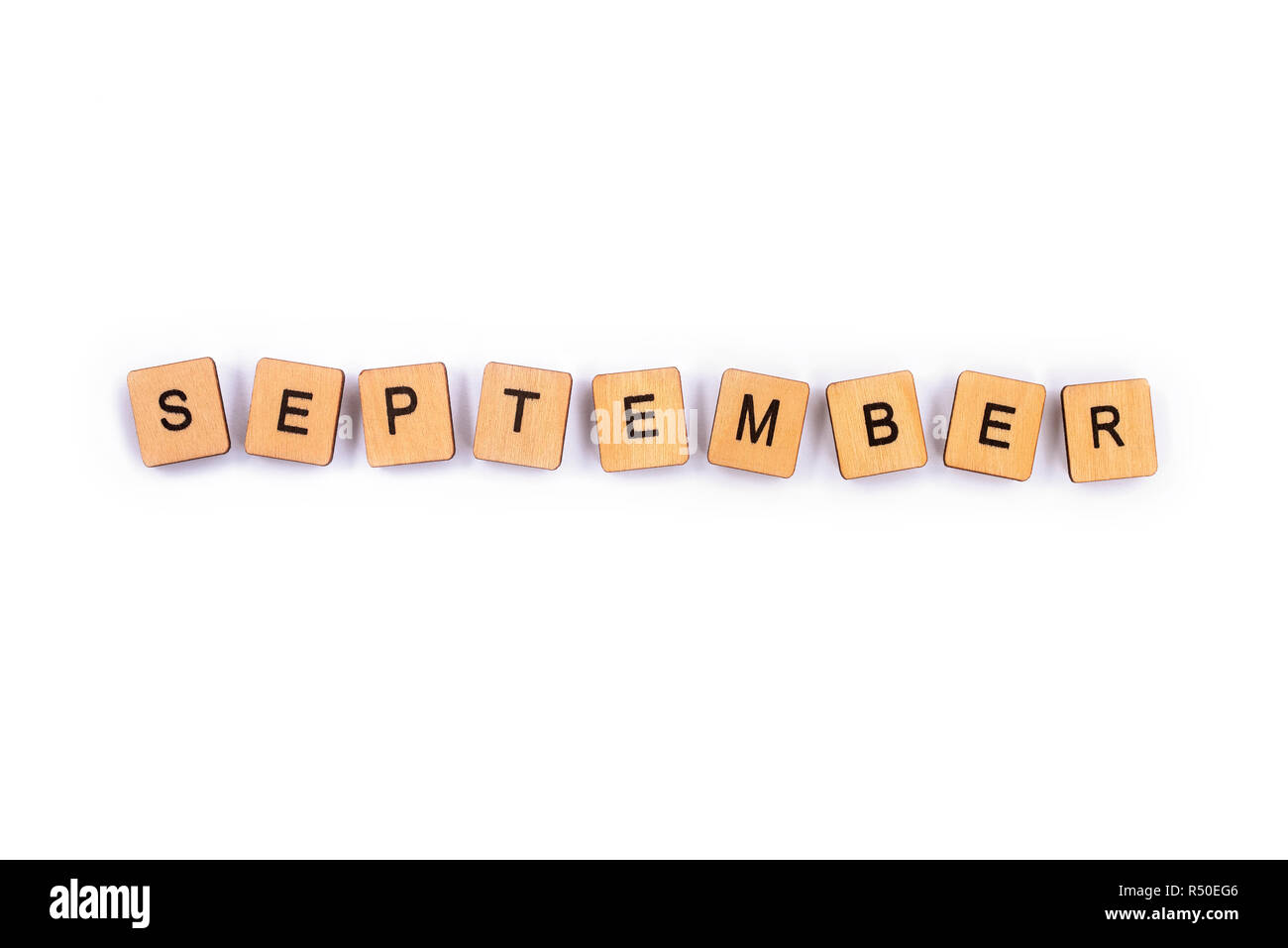 SEPTEMBER, spelt with wooden letter tiles over a plain white background ...