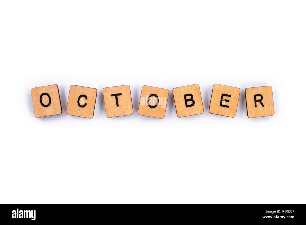 OCTOBER, spelt with wooden letter tiles over a plain white background ...