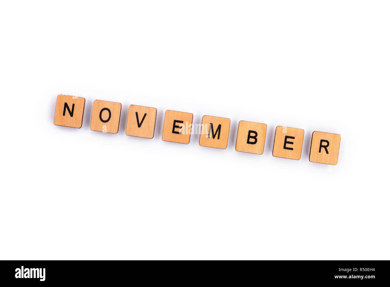 NOVEMBER, spelt with wooden letter tiles over a plain white background ...