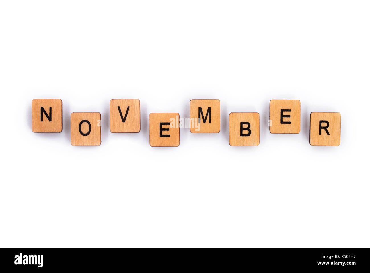 NOVEMBER, spelt with wooden letter tiles over a plain white background ...