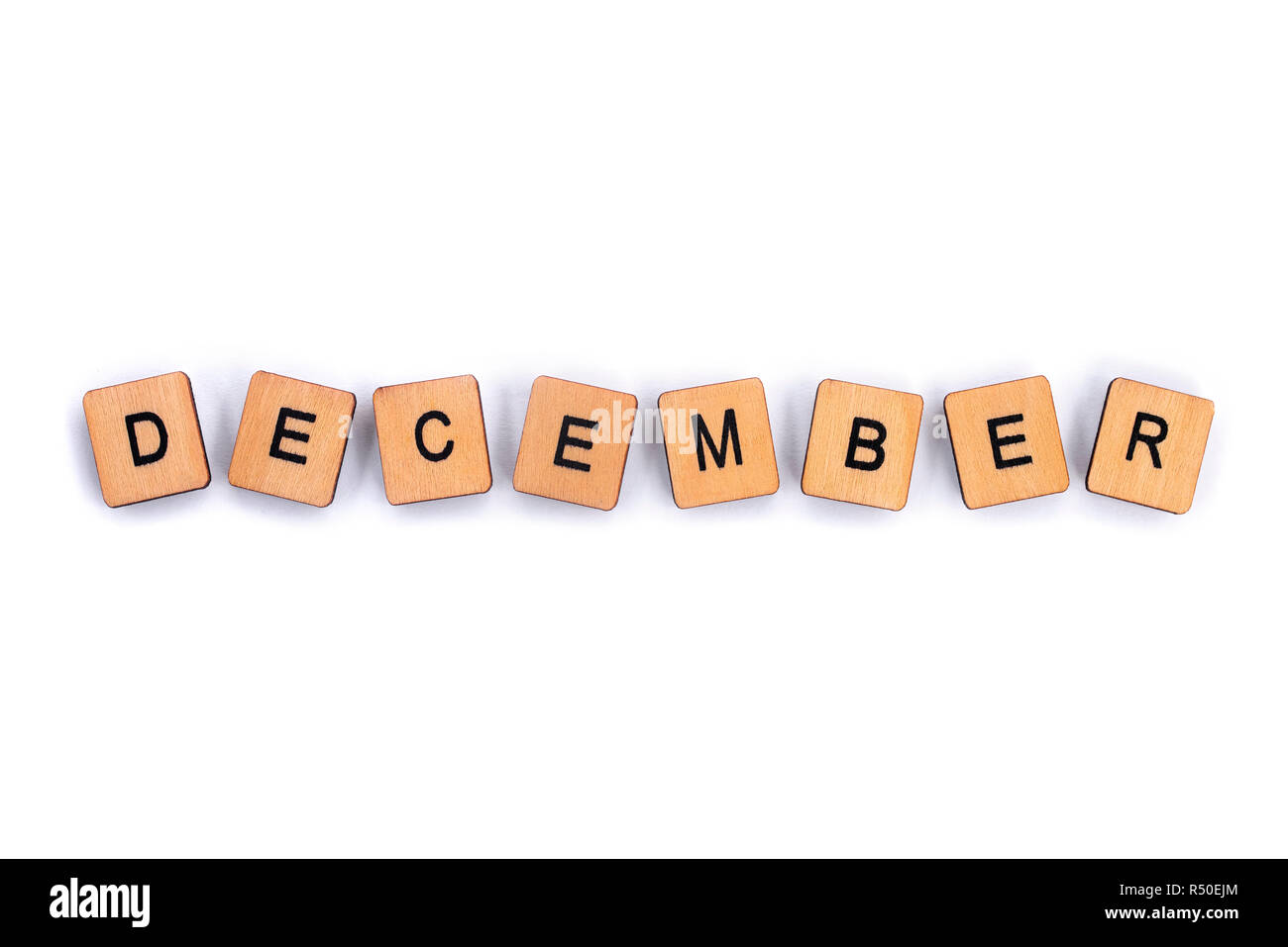 DECEMBER, spelt with wooden letter tiles over a plain white background ...