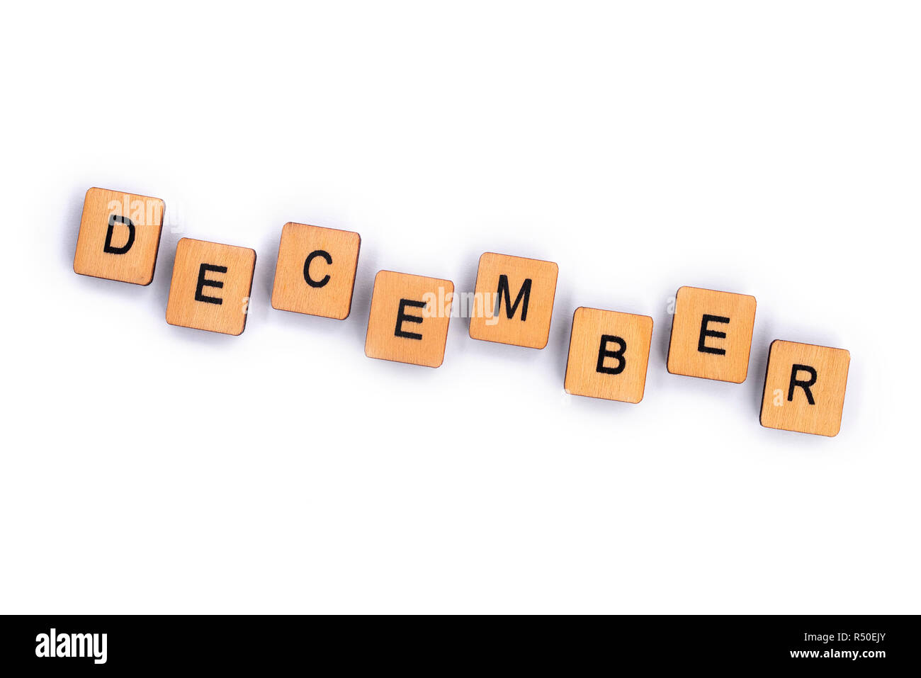 DECEMBER, spelt with wooden letter tiles over a plain white background ...