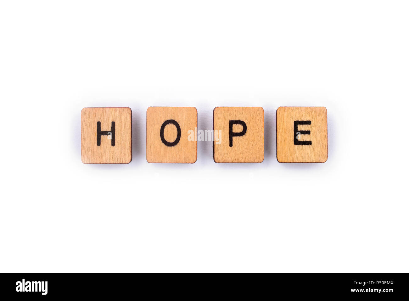 The word HOPE, spelt with wooden letter tiles over a plain white ...
