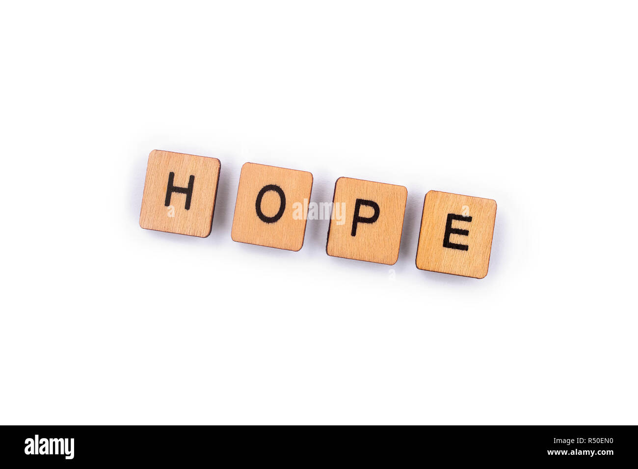 The word HOPE, spelt with wooden letter tiles over a plain white ...