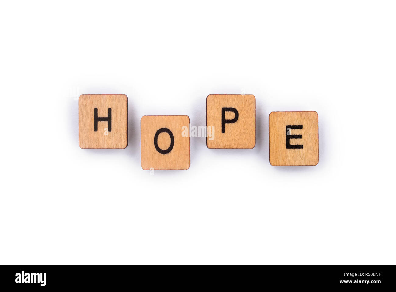 The word HOPE, spelt with wooden letter tiles over a plain white ...