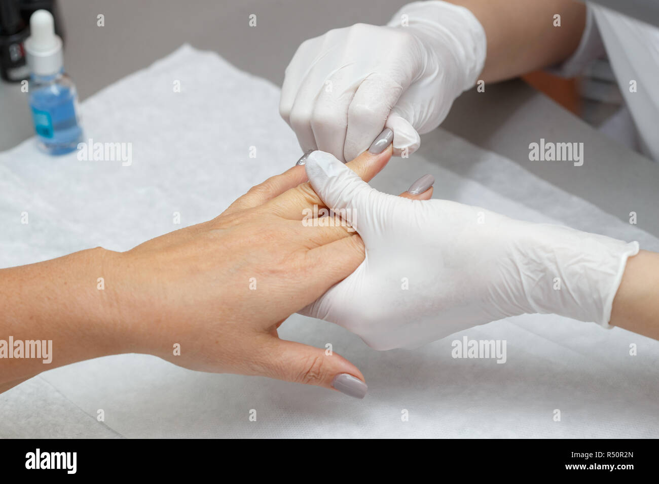 Massage therapist in latex gloves massaging hands of a woman in a ...