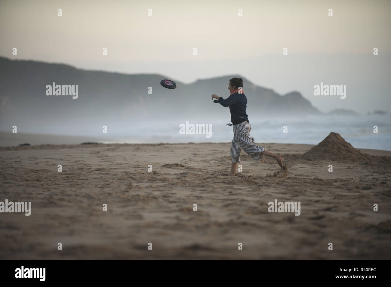 Woman playing frisbee on the beach Stock Photo - Alamy
