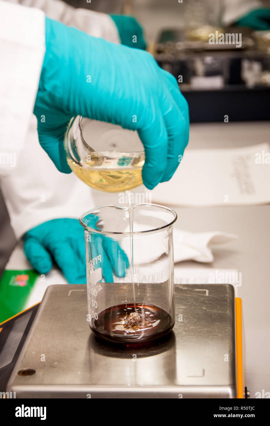 Scientist pouring liquid into glass beaker Stock Photo - Alamy