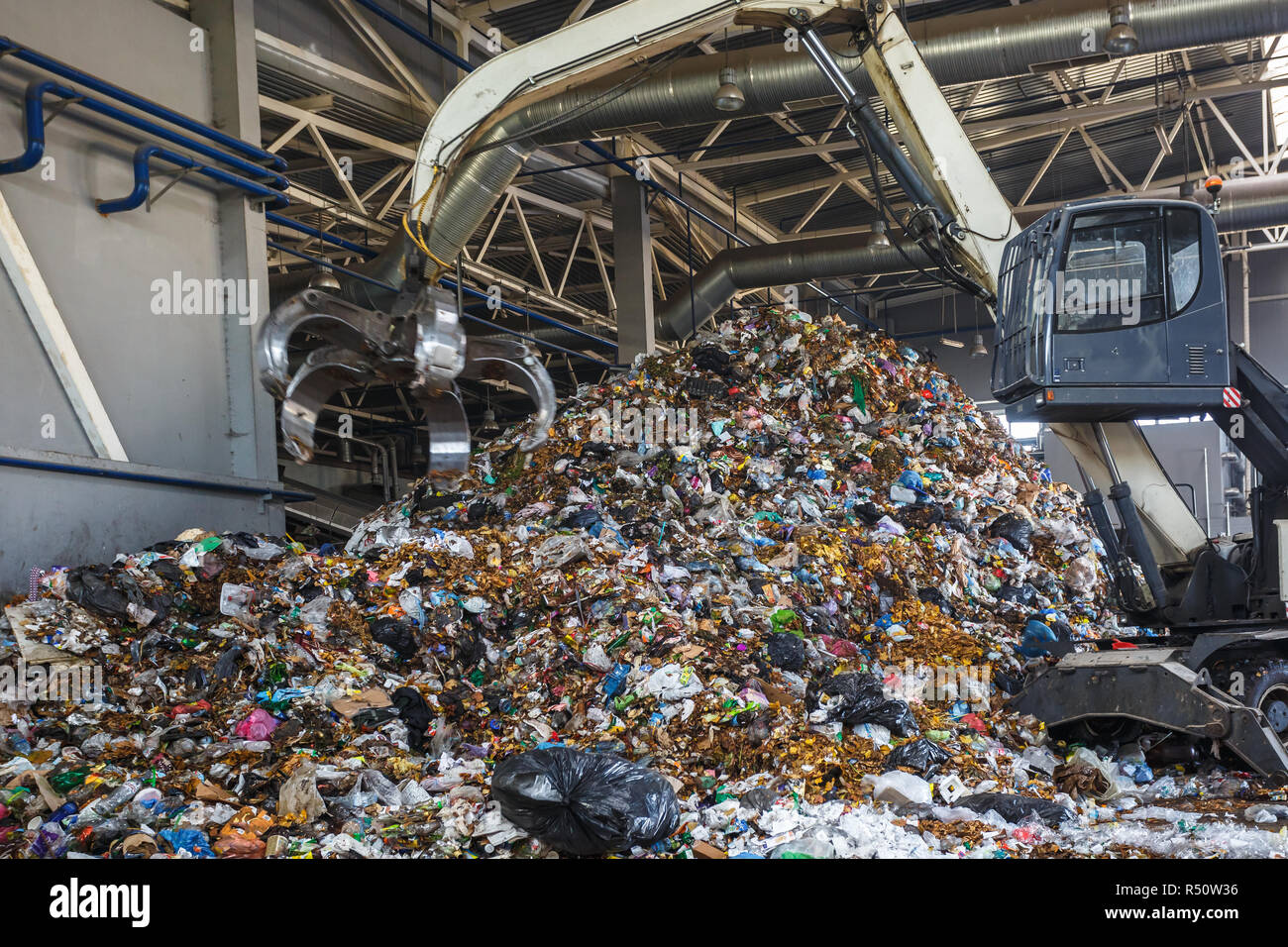 Excavator on primary sorting of garbage at waste processing plant ...