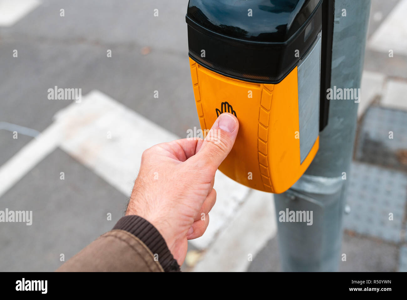 Hand pushing control button on pedestrian crossing to activate the ...