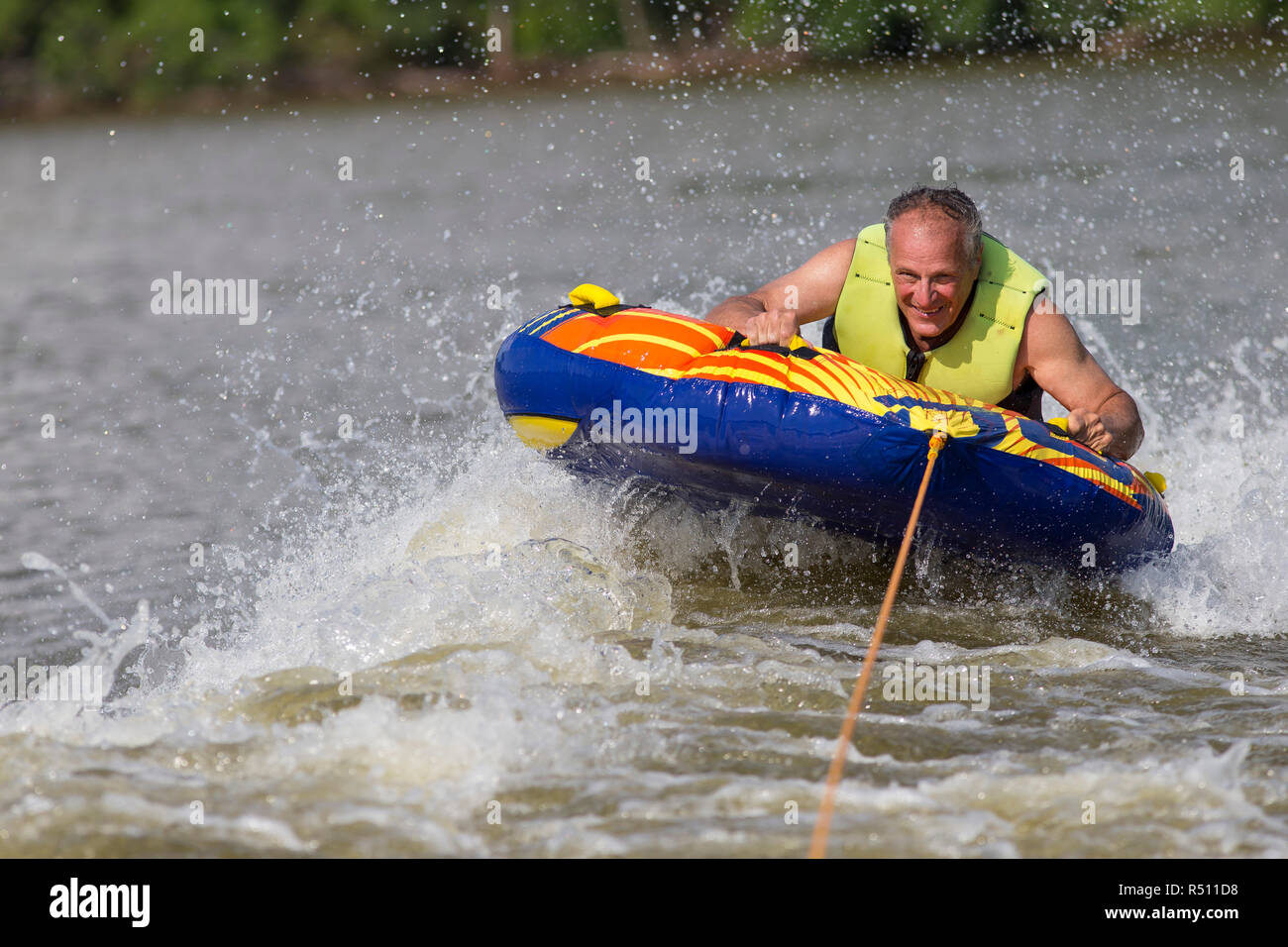 Front view of man having fun tubing on river Stock Photo - Alamy
