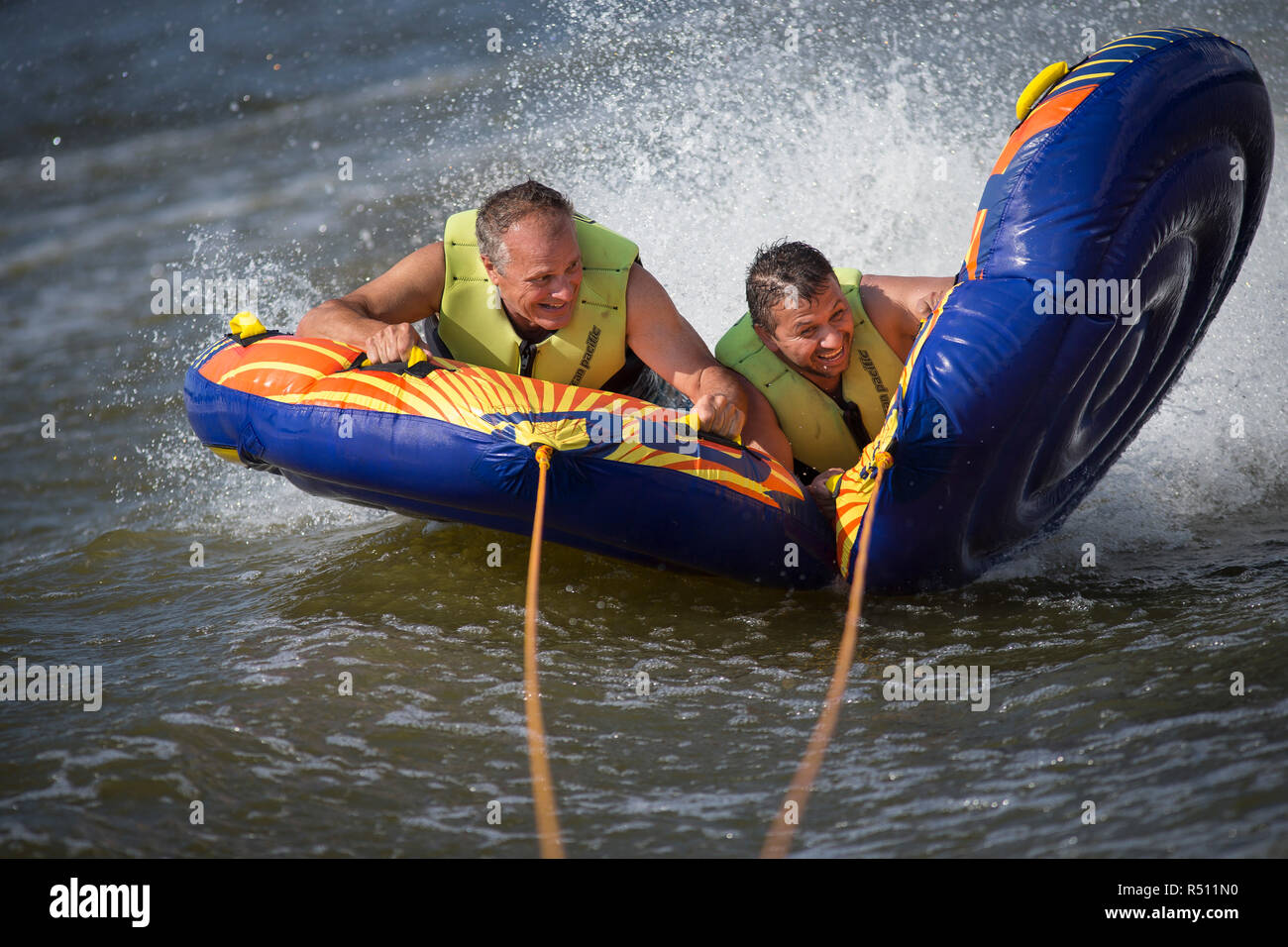 Front view of two men tubing on river Stock Photo - Alamy